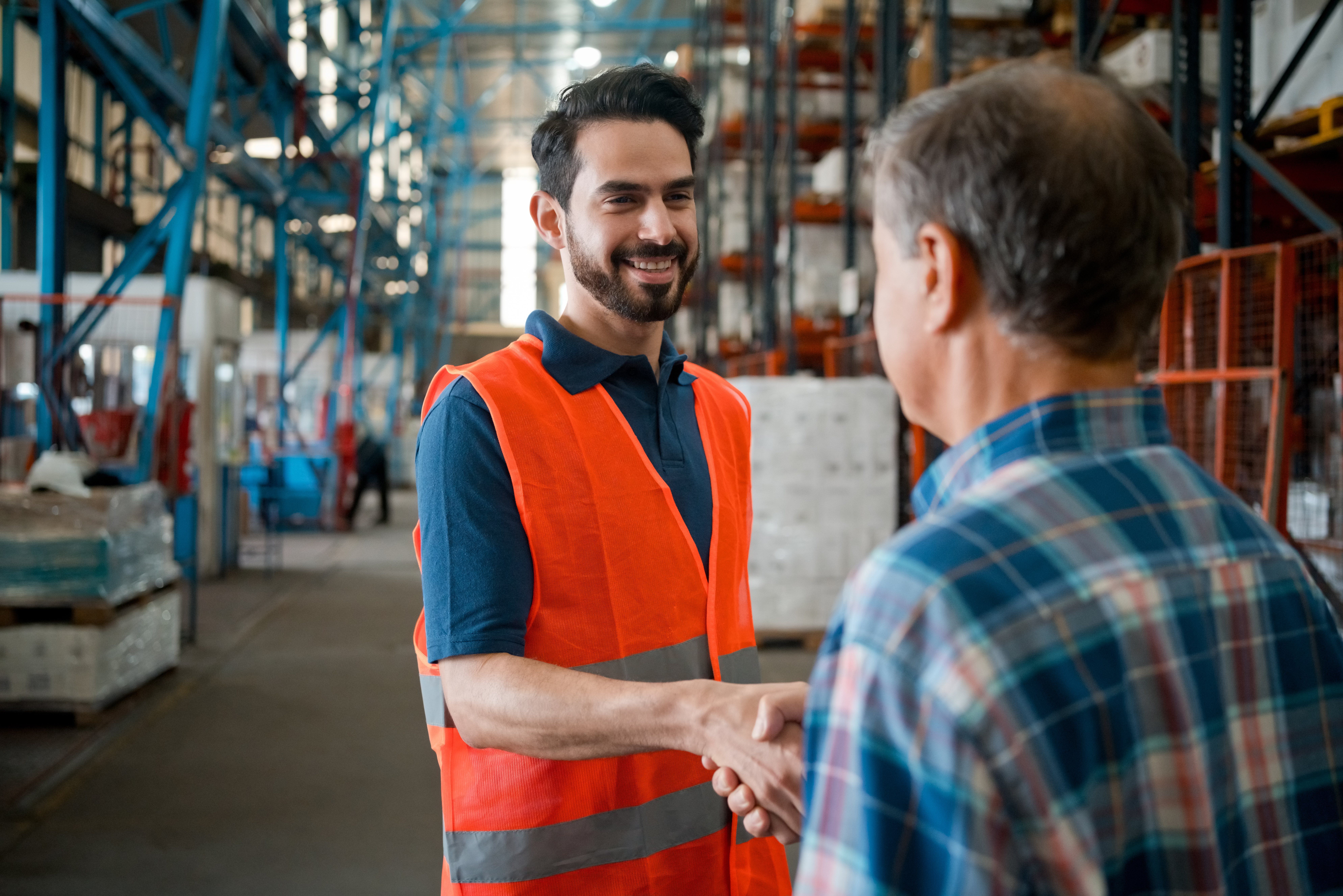 Warehouse managers shaking hands and smiling in a warehouse